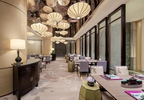 Um saguão de hotel com balcão de recepção, área de estar e grandes janelas.