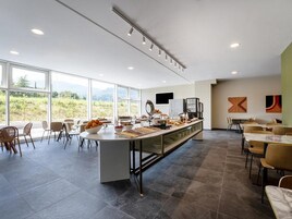 Espaço de refeições moderno com buffet, janelas amplas e vista para o exterior.