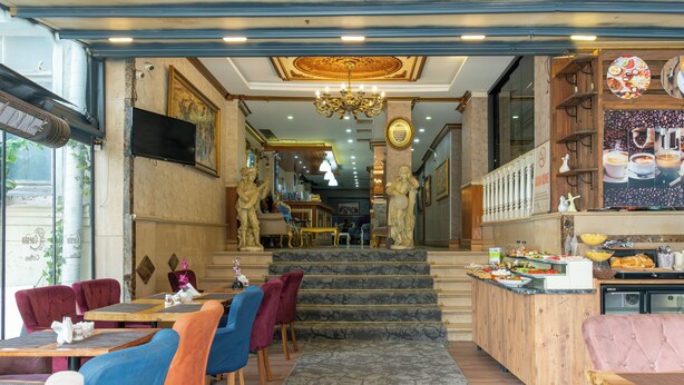 Restaurante com piso de mármore, escadaria central e diversas opções de assentos, incluindo mesas e cadeiras.