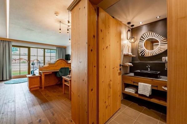 Quarto de madeira com escrivaninha, cadeira e uma janela grande.
