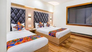 Quarto de hotel com duas camas, uma janela grande e um ventilador de teto.