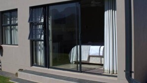 Um edifício moderno com grandes portas de correr de vidro que dão acesso a um quarto com cama e cortinas.
