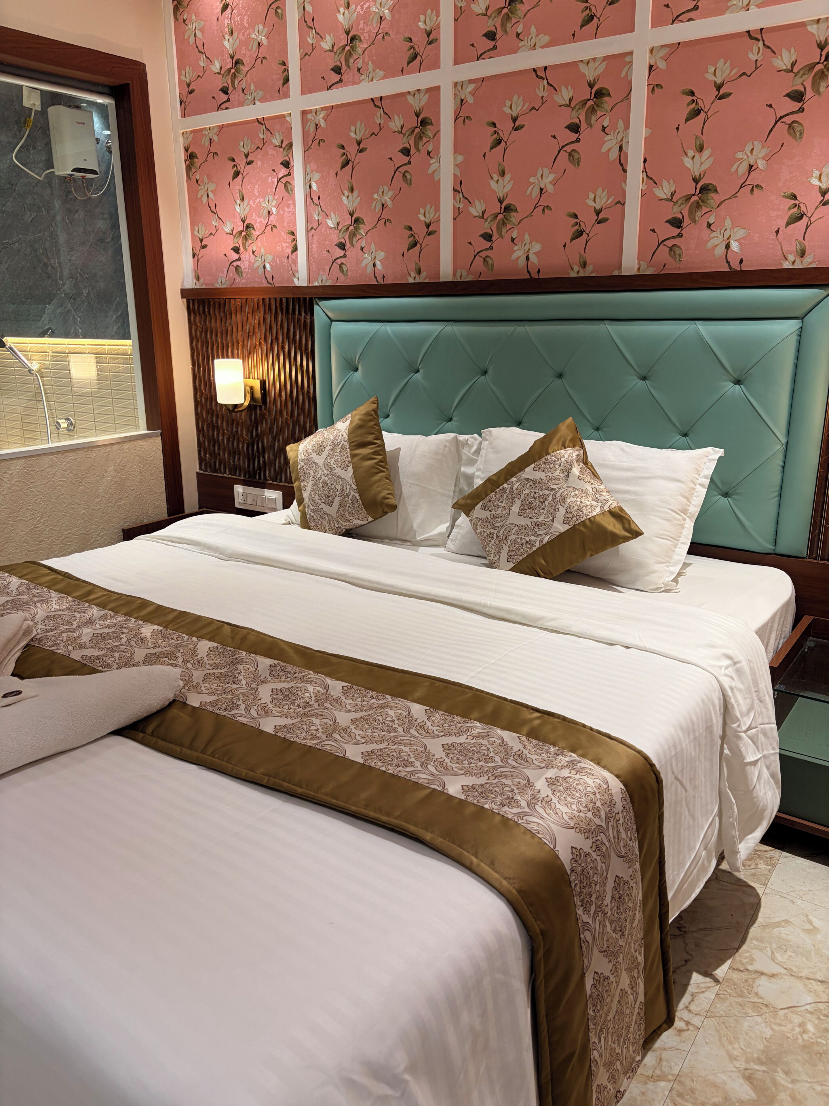 Quarto de hotel com cama, mesa de cabeceira, aquecedor fixado na parede e janela com chuveiro.