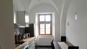 Cozinha compacta com janela, mesa de jantar e micro-ondas.