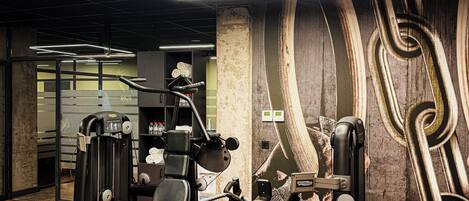 Uma academia com equipamentos de ginástica, piso de madeira e uma parede com design metálico.