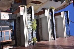 Um edifício moderno com fachada de pedra, janelas amplas e uma varanda com piso de madeira.