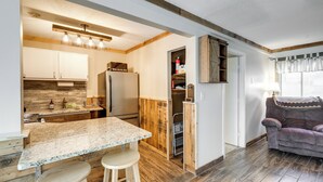 Uma cozinha com bancada de mármore, piso de madeira e geladeira embutida.
