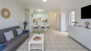 Uma sala de estar moderna com sofá, mesa de centro e área de jantar com cadeiras e mesa.