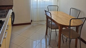 Uma cozinha com fogão, pia e mesa de jantar com quatro cadeiras.