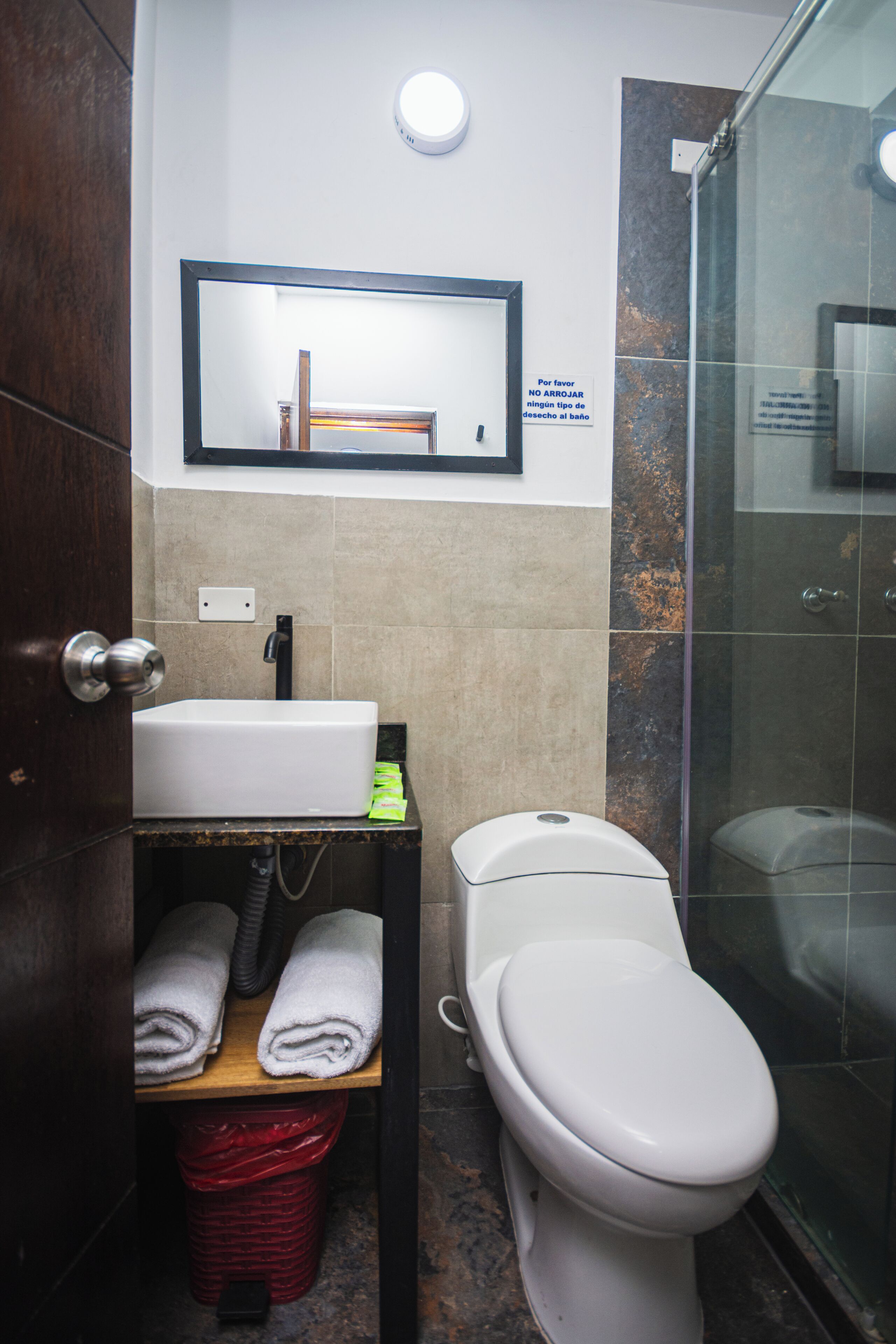 Uma casa de banho compacta com uma sanita branca, uma casa de banho e um chuveiro com divisória de vidro.