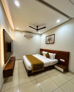 Quarto de hotel moderno com uma cama, uma TV, um ventilador de teto e um aparelho de ar condicionado.