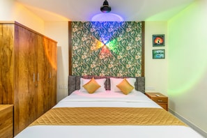 Quarto com cama, guarda-roupa de madeira, papel de parede floral e dois quadros pendurados na parede.