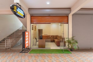 Recepção de hotel com balcão, escada e placa indicando os quartos.