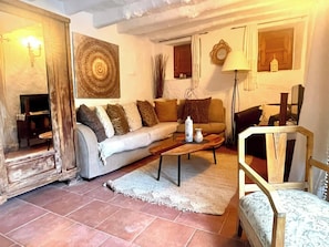 Uma sala de estar com sofá, mesa de centro, luminária e espelho.