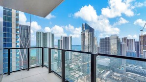 Um edifício alto com varanda de vidro e vista para a cidade.