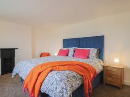 Um quarto com cama, mesa de cabeceira, cômoda e lareira.