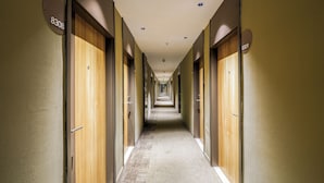Corredor de hotel com portas numeradas 8308 e 8309, pisos carpetados e teto com iluminação embutida.
