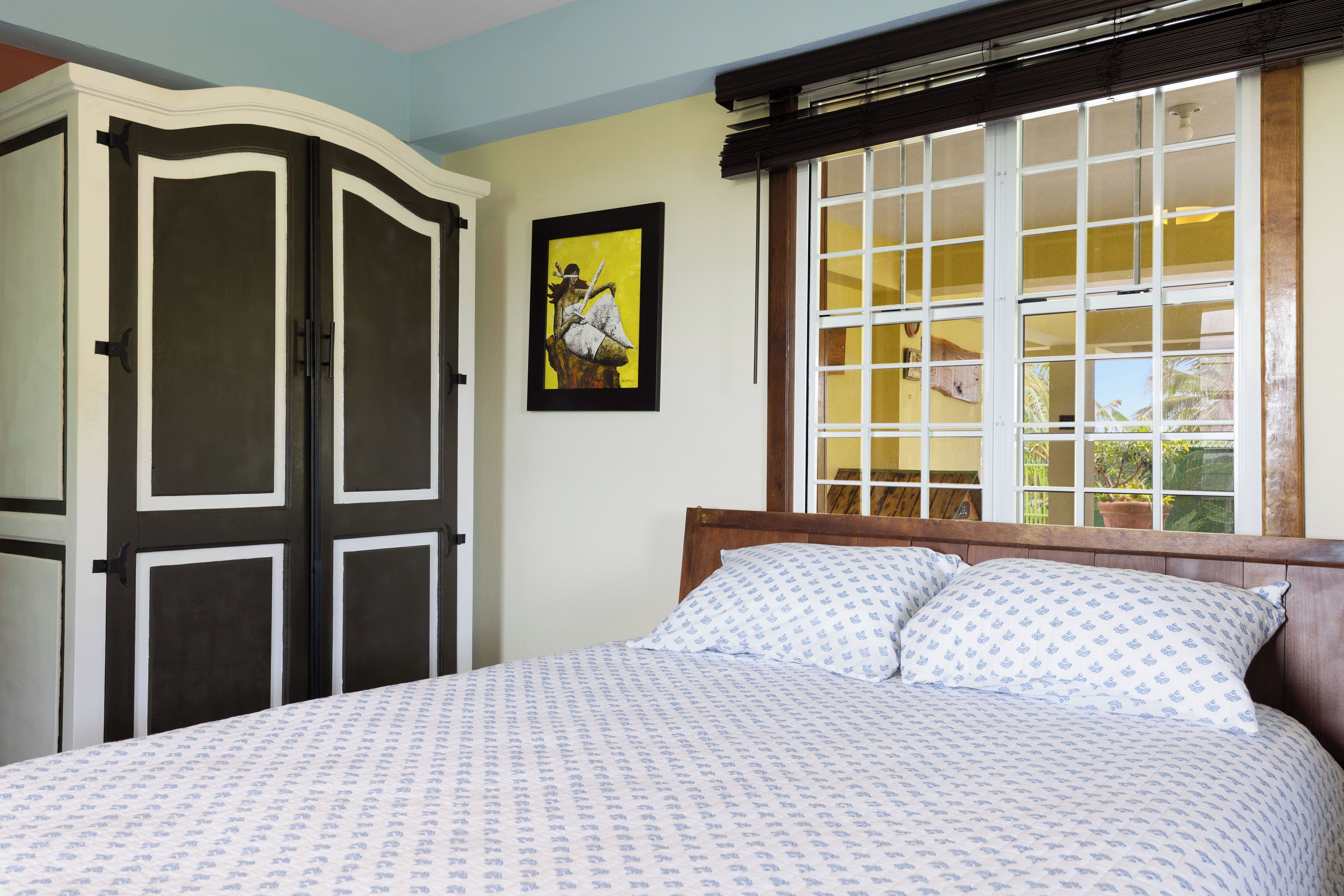Quarto com cama, guarda-roupa e janela com vista.