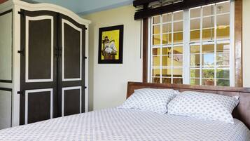 Quarto com cama, guarda-roupa e janela com vista.