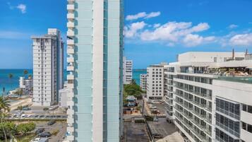 Um hotel alto com vista para o oceano, área de estacionamento e edifícios próximos.