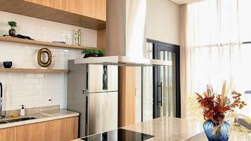 Uma cozinha moderna com ilha central, eletrodomésticos de aço inoxidável, armários de madeira e uma grande janela que oferece iluminação natural.