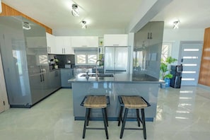 Uma cozinha moderna com uma ilha central, banquetas de bar e eletrodomésticos embutidos.