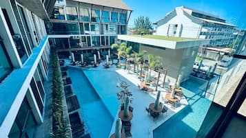 Um edifício moderno com um jardim no terraço, piscina e áreas de estar ao ar livre.