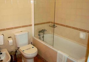 Um banheiro com vaso sanitário, pia e banheira.