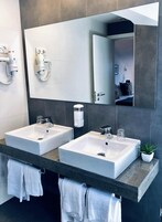 Uma casa de banho moderna com duas pias, um espelho grande e um porta-toalhas.