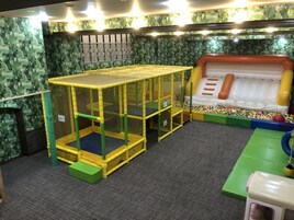 Uma área de recreação com um trampolim, uma estrutura de escalada e uma piscina de bolinhas.
