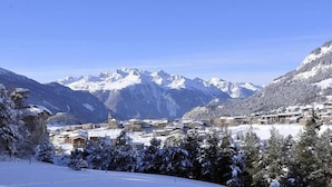 Uma cidade coberta de neve com montanhas ao fundo.