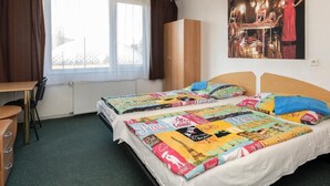 Quarto com cama, escrivaninha, cadeira, guarda-roupa e janela com cortinas.