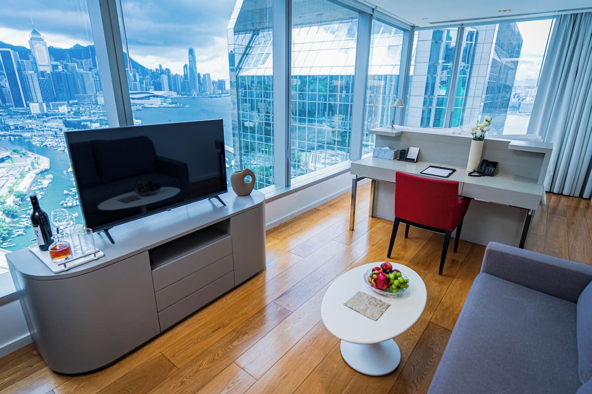 Uma sala de estar moderna com uma TV grande, área de jantar e vista para o horizonte urbano.