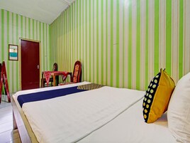 Quarto com uma cama, uma mesa com cadeiras, uma porta e uma parede listrada.