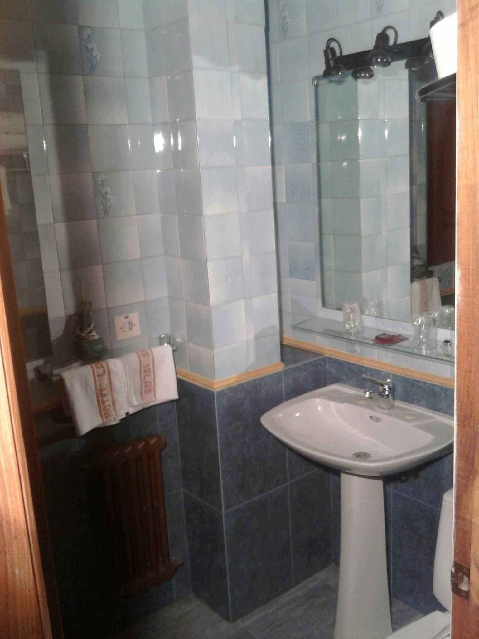 Casa de banho com lavatório branco, espelho e azulejos azuis.