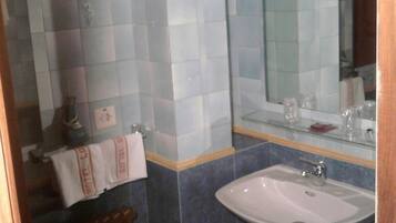 Casa de banho com lavatório branco, espelho e azulejos azuis.