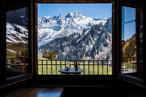 Quarto com vista para montanhas cobertas de neve pela janela.