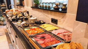Buffet com diversas opções de comida, incluindo carnes, queijos e legumes.