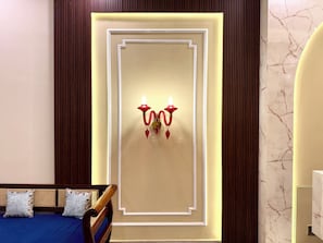 Quarto com uma cama, um candelabro fixado na parede e uma parede com padrão marmorizado.