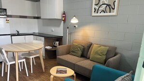 Um espaço compacto com cozinha compacta, sofá, mesa pequena e poltrona azul.