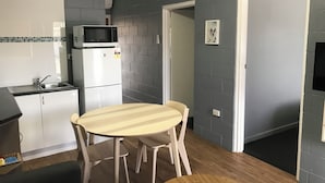 Cozinha compacta com micro-ondas, geladeira e mesa de jantar com cadeiras.