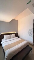 Quarto de hotel moderno com cama, mesa de cabeceira e design decorativo na parede.