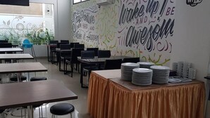 Uma área de jantar moderna com mesas, cadeiras e um mural inspirador na parede.