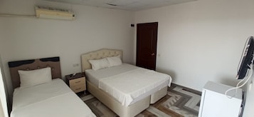 Quarto com duas camas, uma mesa de cabeceira, um guarda-roupa, ar condicionado e uma televisão.