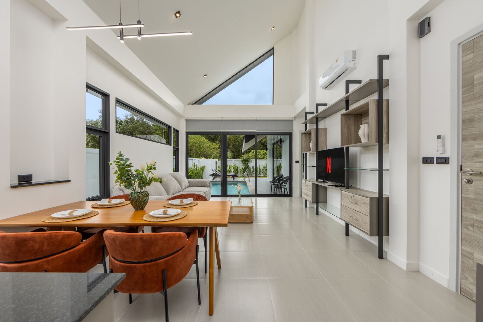 Cozinha moderna com área de jantar, eletrodomésticos embutidos e vista para o exterior.
