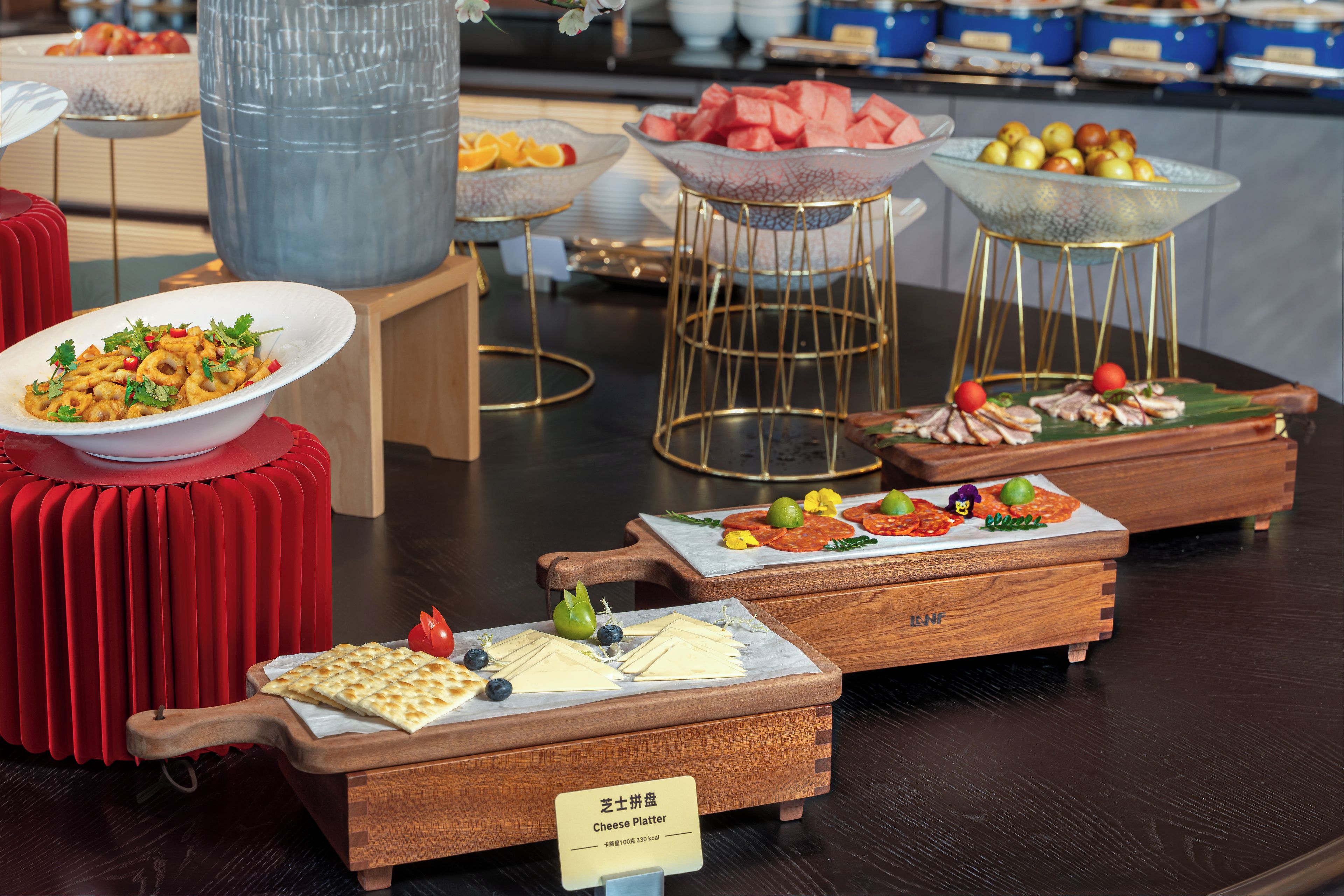 Buffet com diversos alimentos e um aviso indicando a quantidade de calorias do prato de queijos.