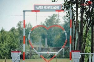Um portão em formato de coração com uma placa acima que diz 'NAMIR GREEN RESORT'.
