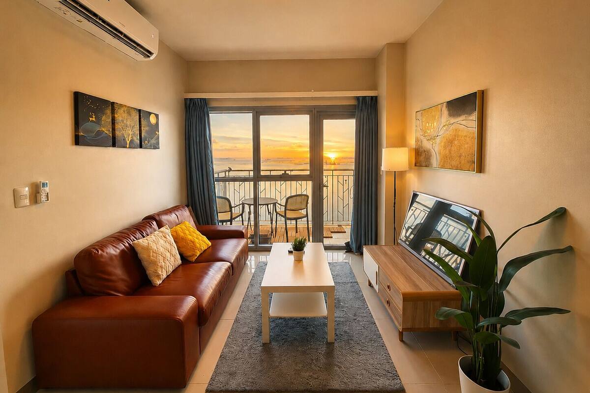 Sala de estar com sofá, mesa de centro, televisão e varanda com vista.