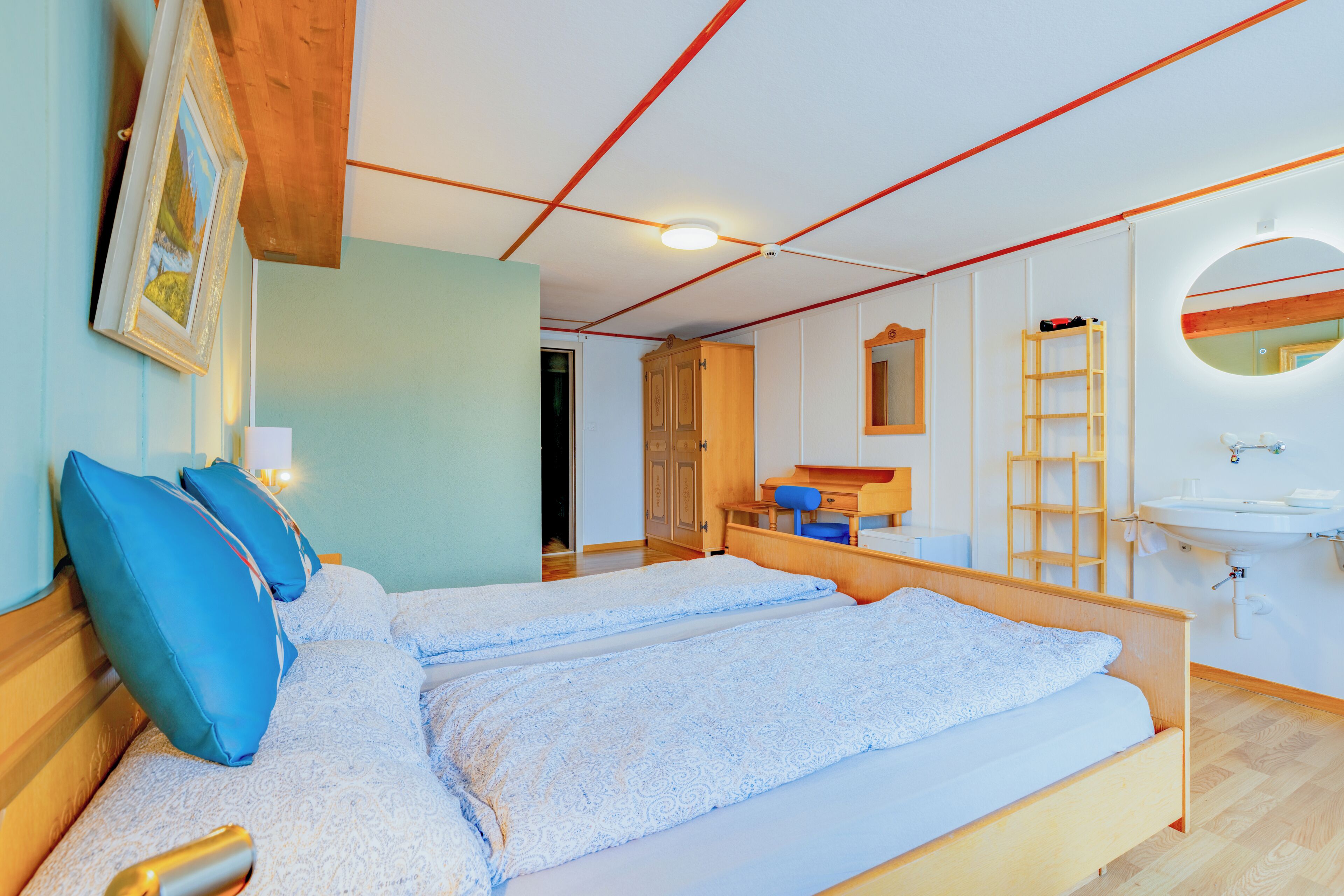 Quarto com uma cama grande, cabeceira de madeira, mesa de cabeceira, espelho, guarda-roupa de madeira e banheiro com pia e espelho.