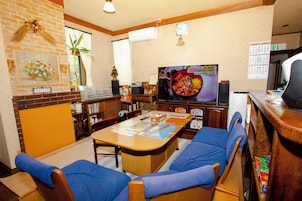 Uma sala de estar com sofá, mesa de centro, televisão e lareira.